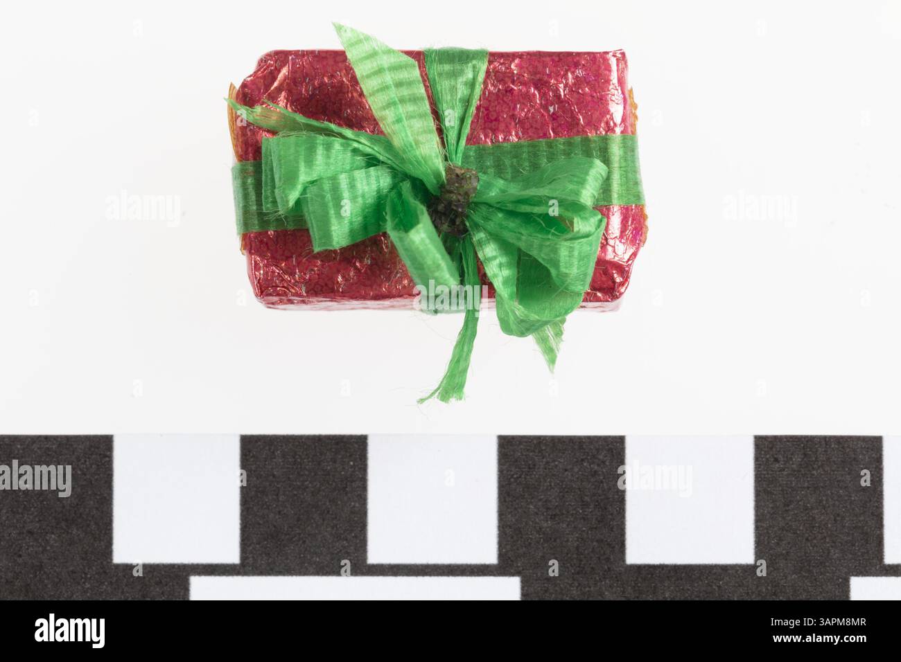 This item is a miniature toy doll wrapped in red foil and tied with a ...