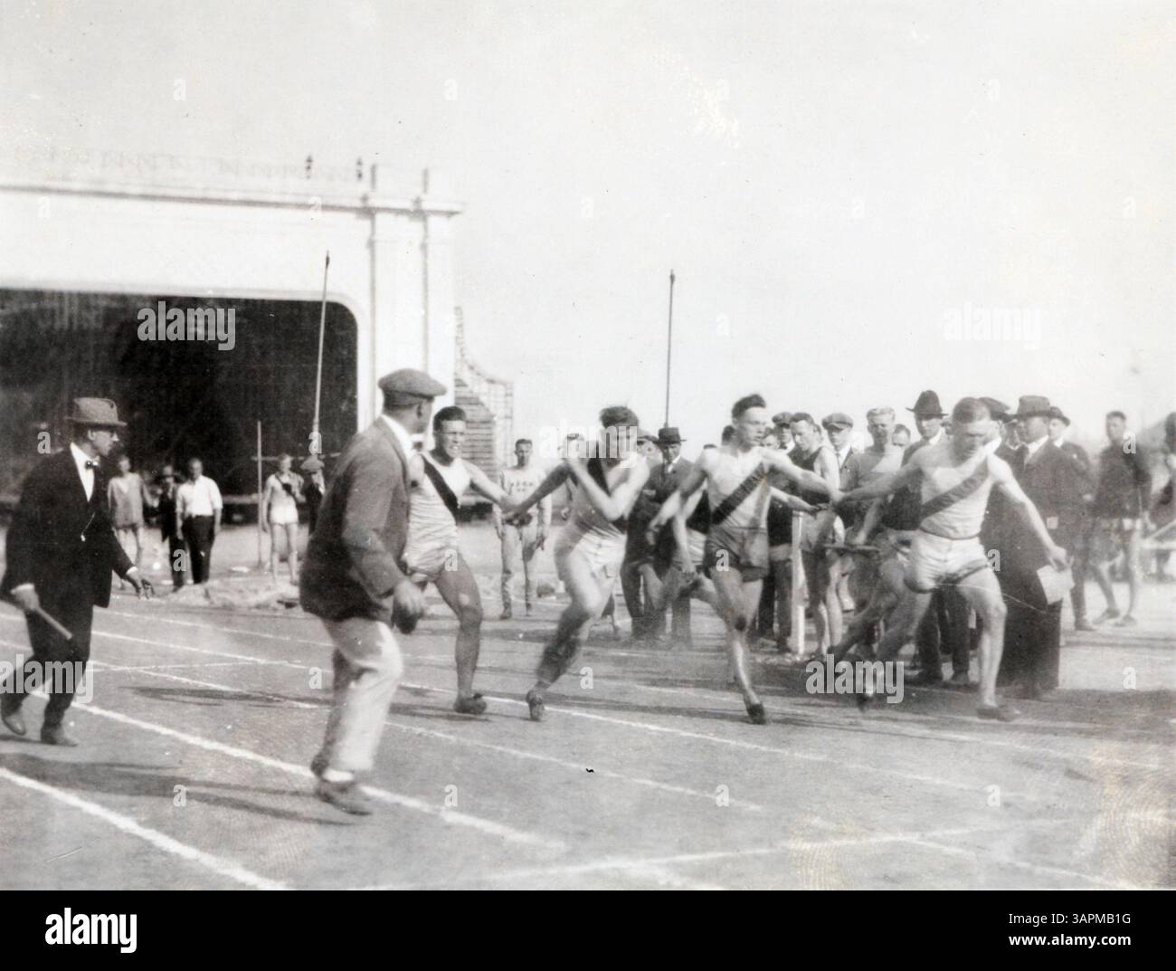 This black and white photo captures a baton pass during a relay race at ...