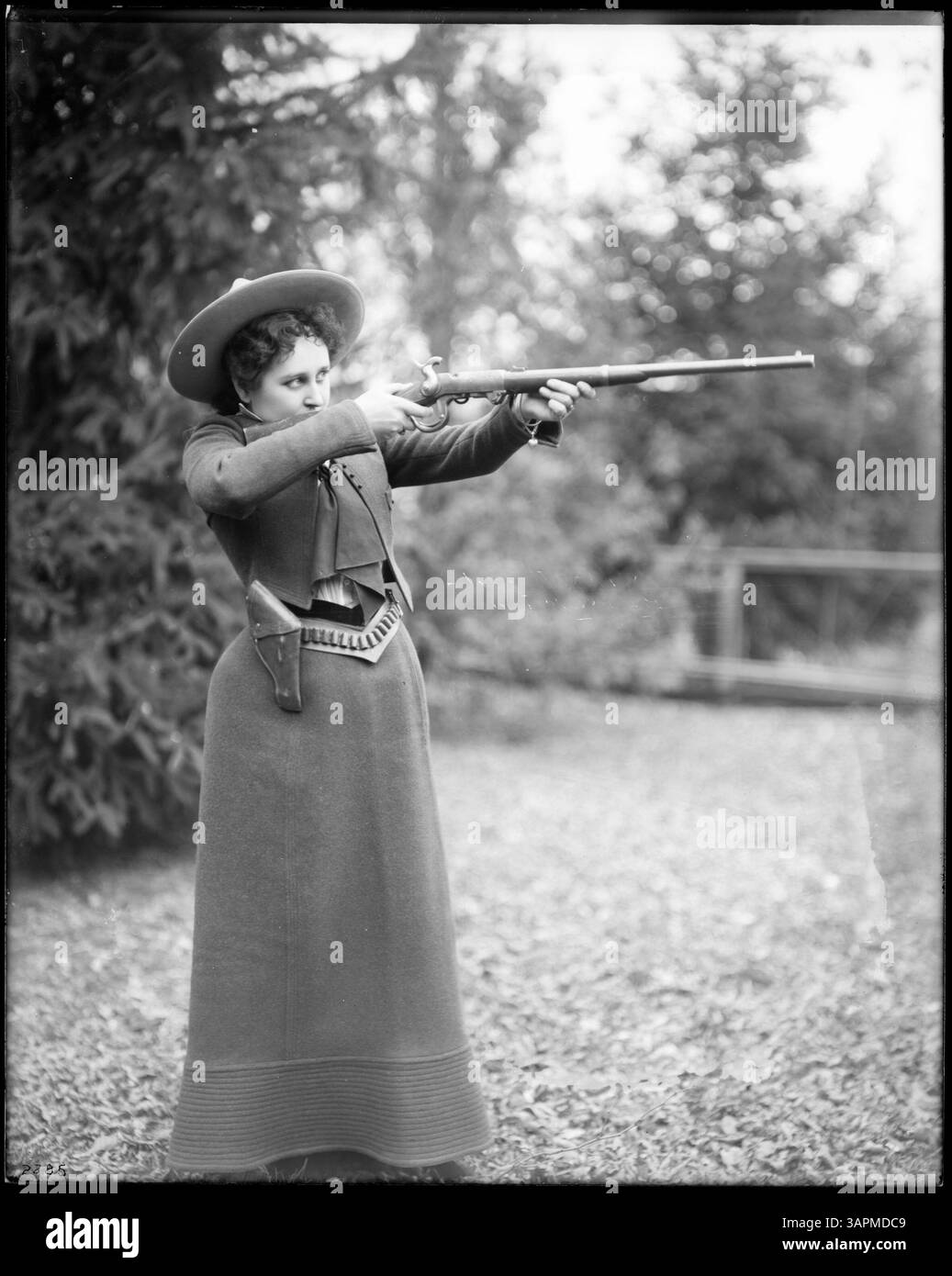 This photograph features Alice Archer in a shooting costume, holding a ...