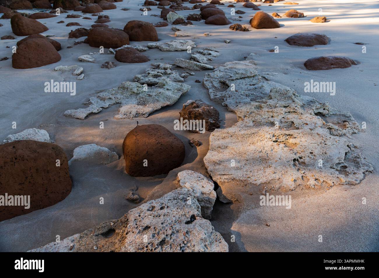 Rocky shoreline with unique formations and sandy textures in warm ...