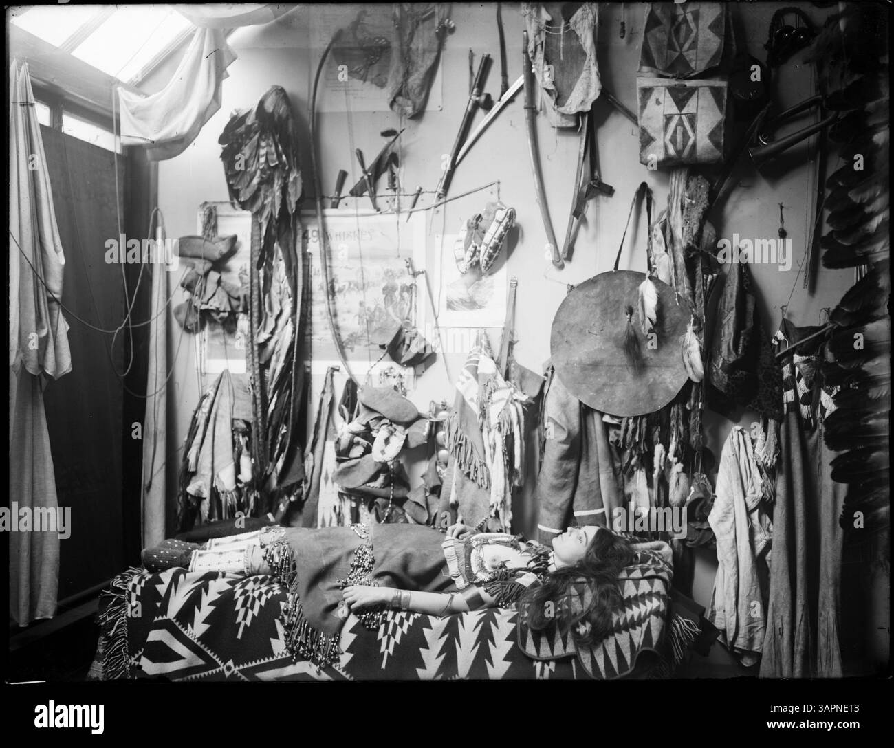 Photograph of a young Native American woman lying on a couch adorned ...