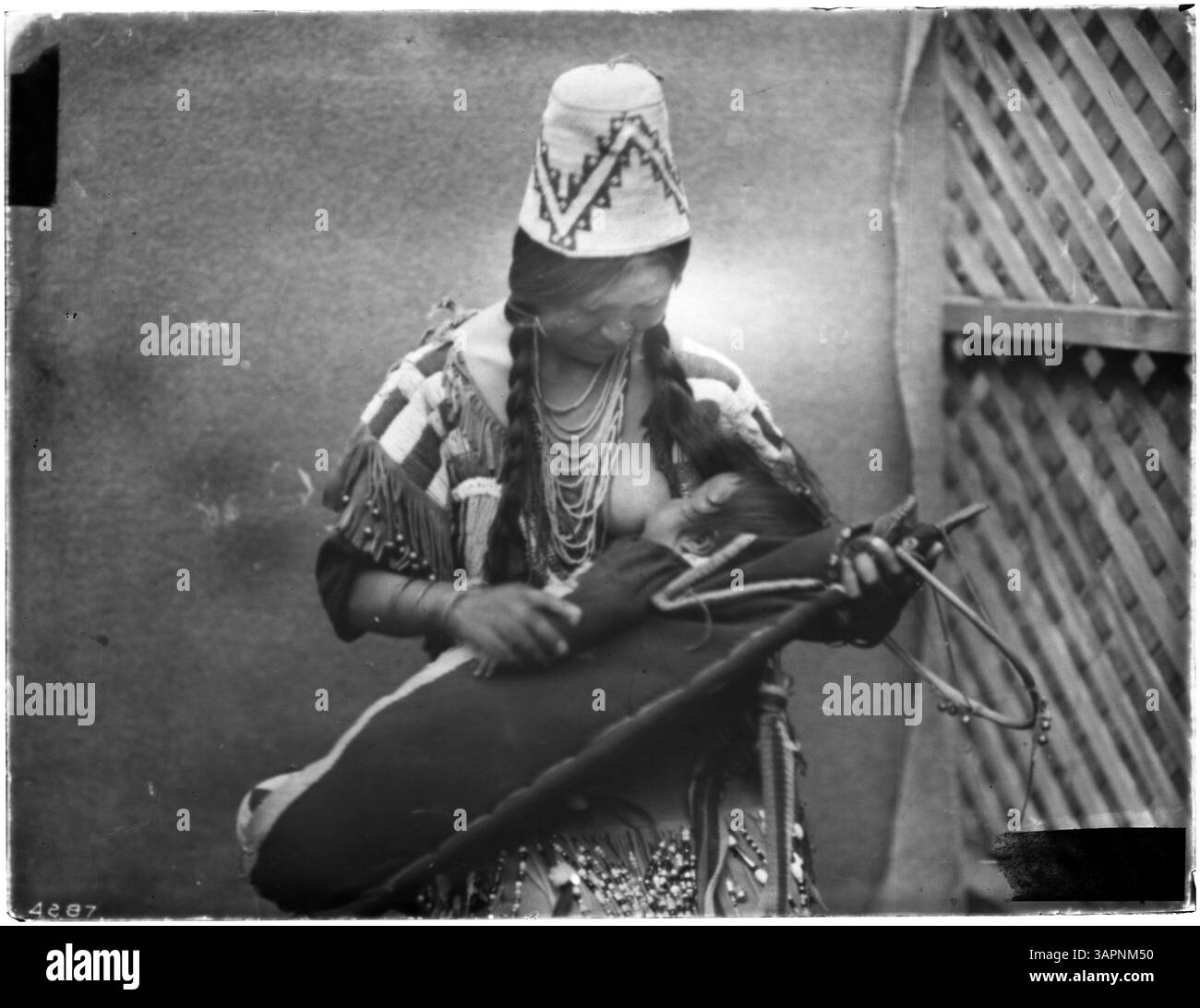 The image captures a Native American woman nursing her child ...