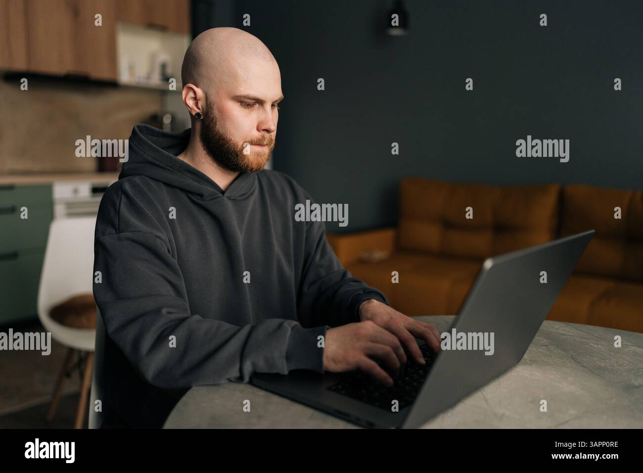 Focused programmer wearing dark hoodie typing code on laptop computer ...