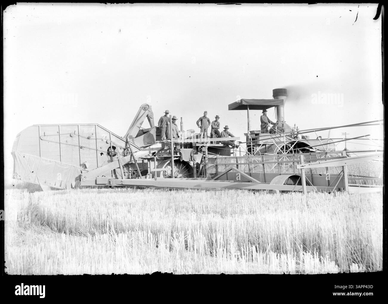 Photograph by Lee Moorhouse of a tractor-drawn combine from a side view ...