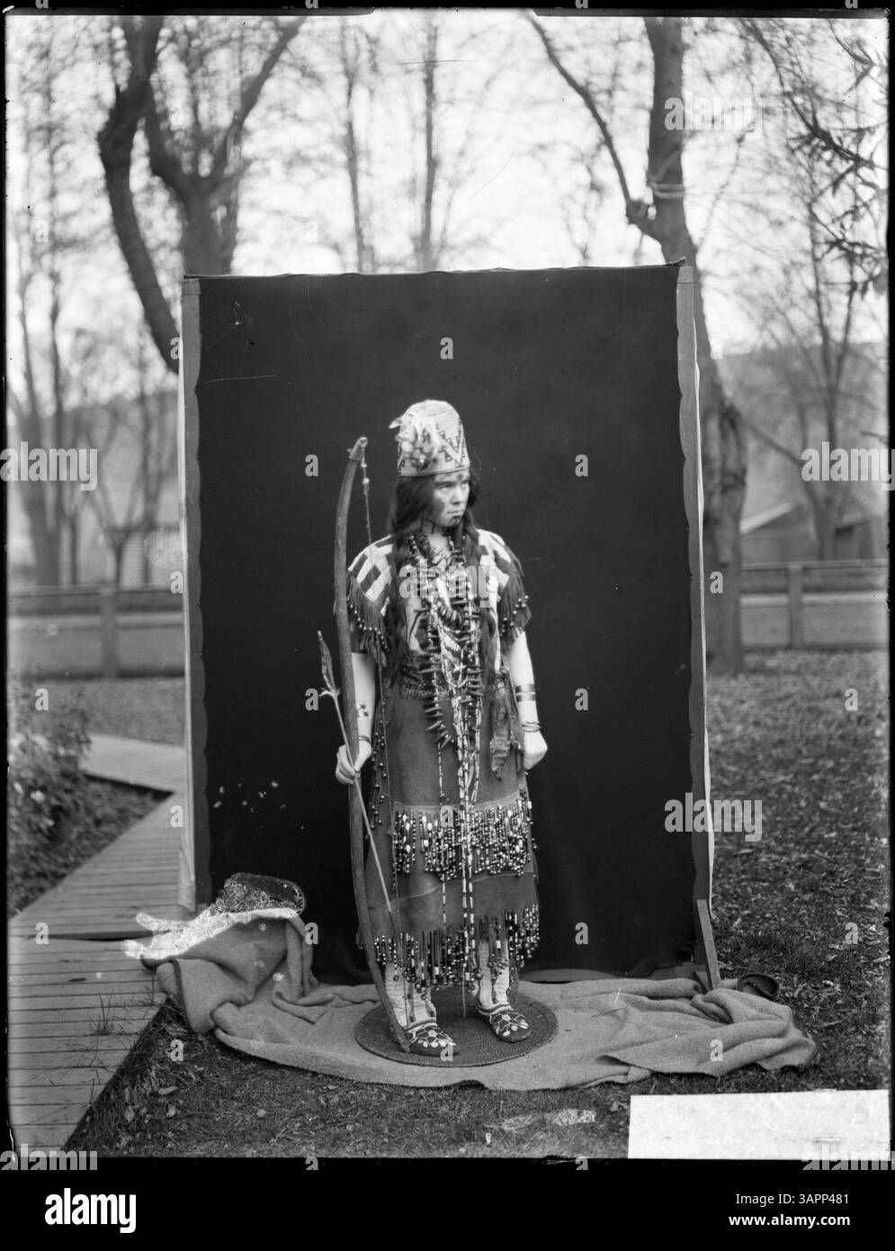 This photograph features a Native American woman in traditional costume ...