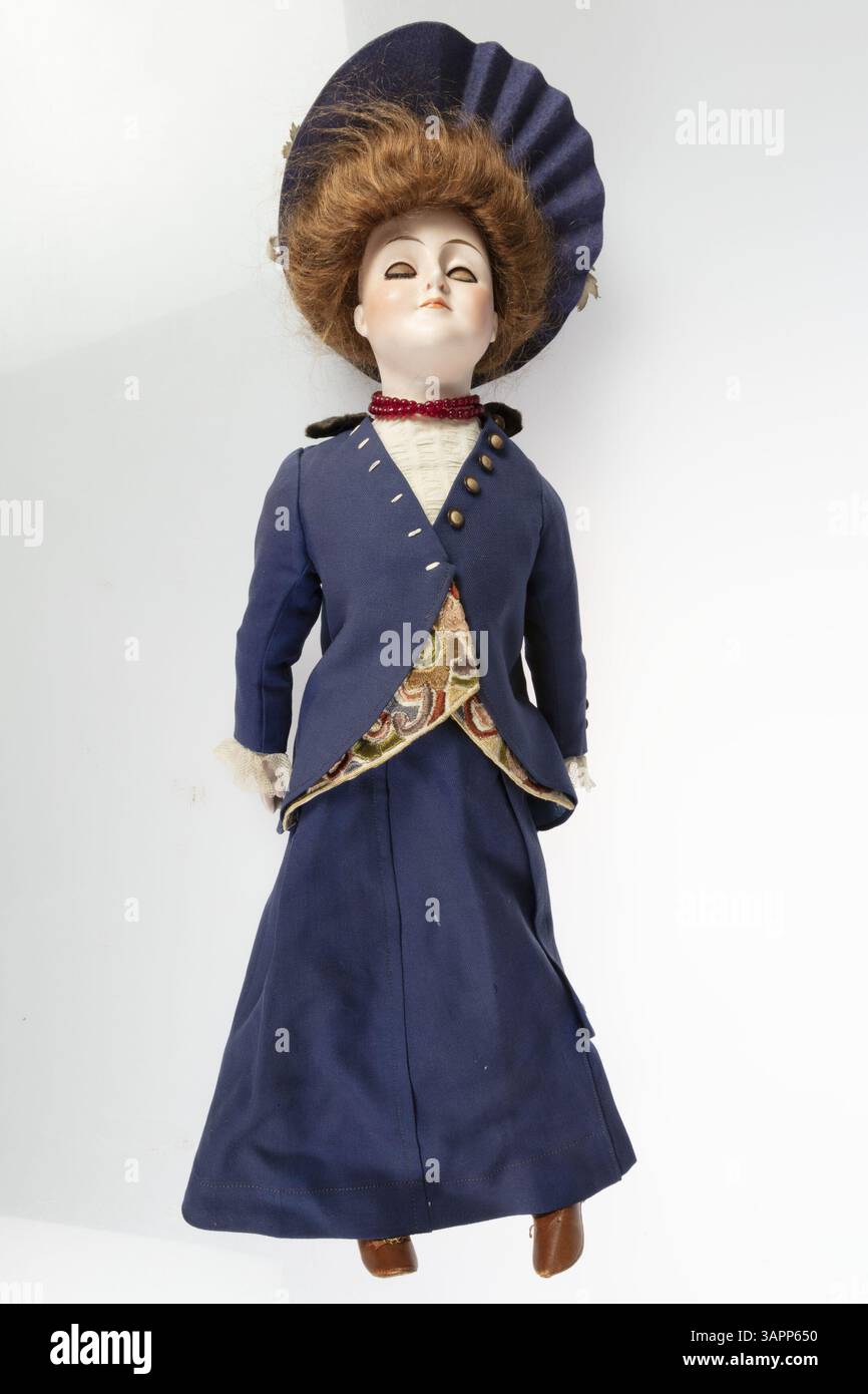 A bisque doll dressed in a blue skirt and jacket with a matching hat ...