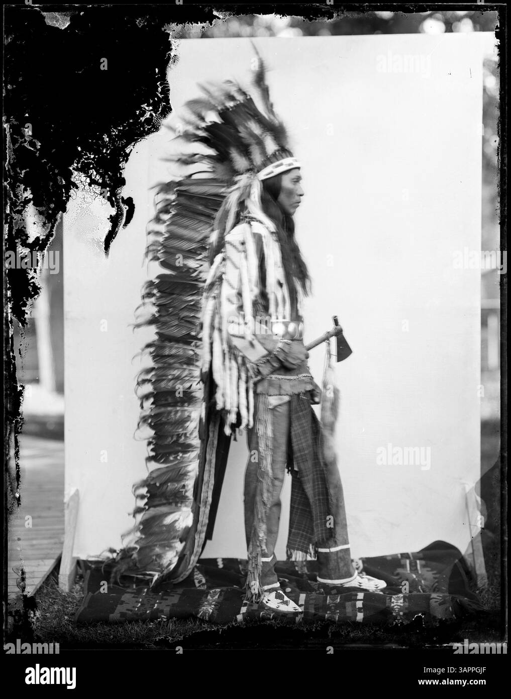 Photograph of a tribal man in regalia holding a hatchet. Taken by Lee ...