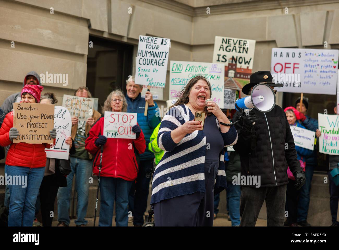 Protesters hold placards and chant through a megaphone during a rally ...