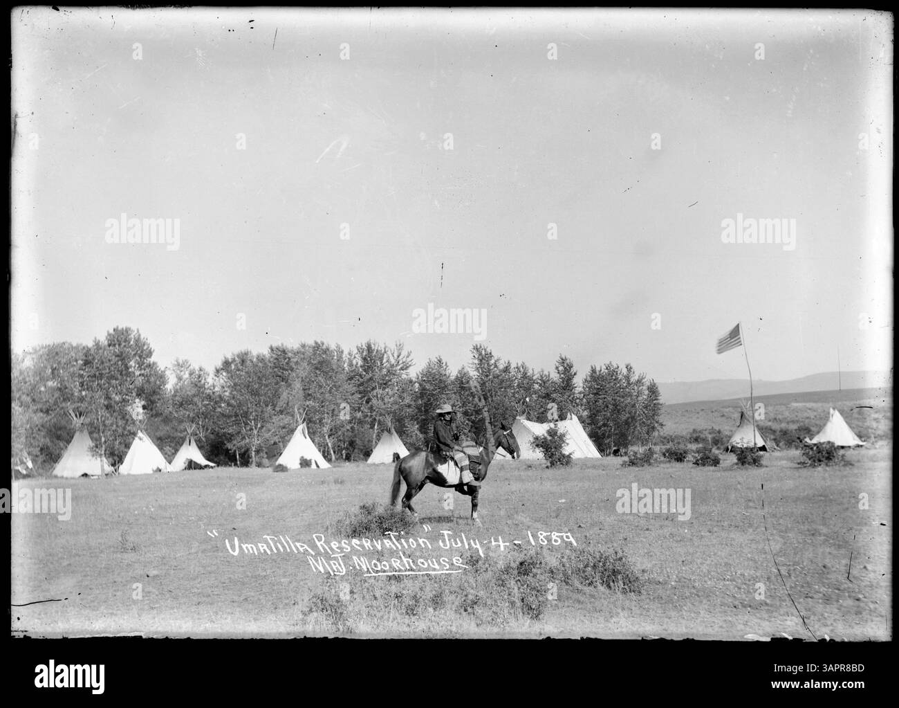 Photograph by Lee Moorhouse of a man on horseback near a ring of tipis ...