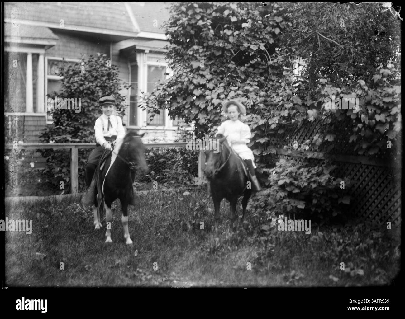 The image depicts a boy and girl on ponies, capturing a moment of rural ...