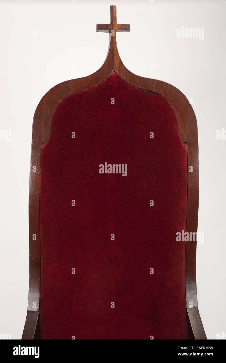A high-backed priest's chair featuring a red velvet upholstered seat ...