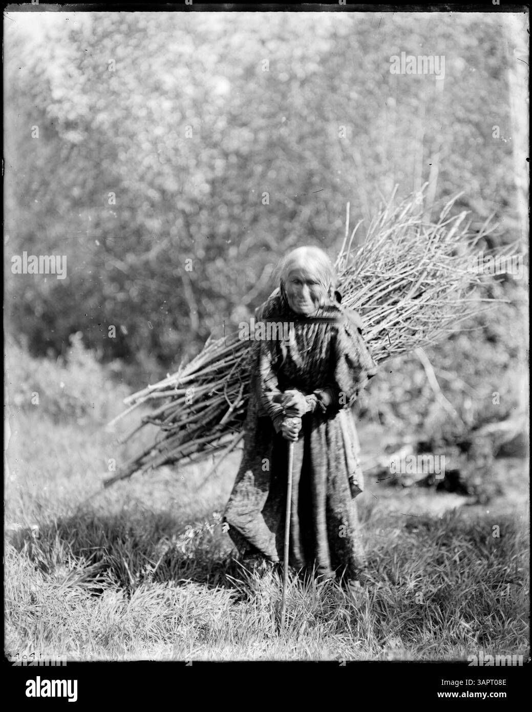 The photograph shows To-Ka-Mappo, an elderly Nez Perce woman, carrying ...