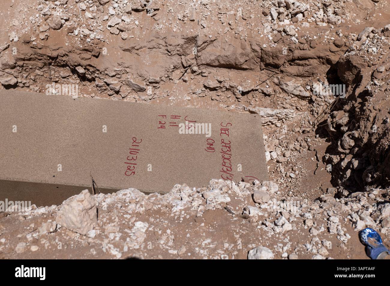 Close-up of a cardboard coffin with handwritten forensic identification, prior to burial in a ...