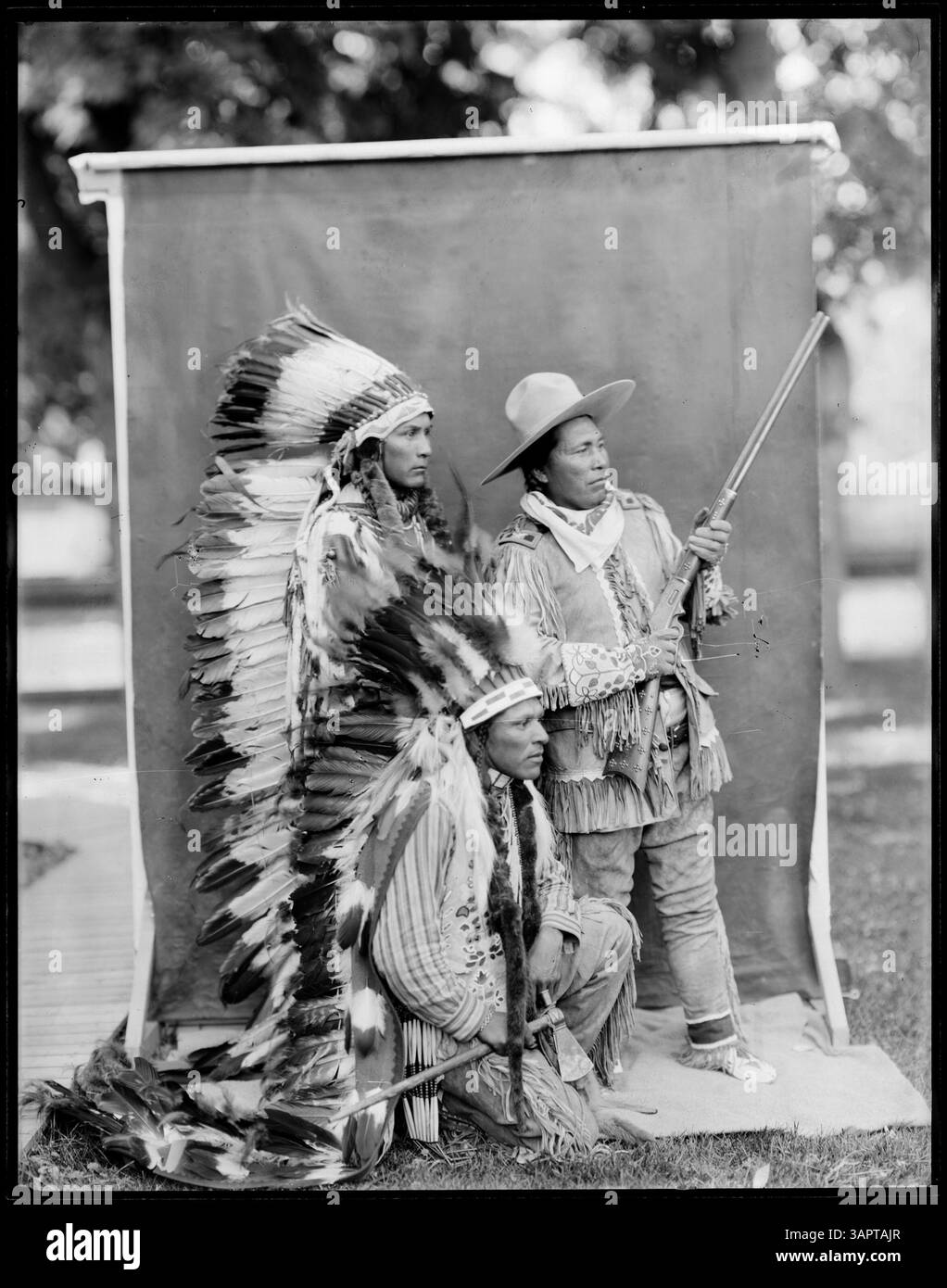 This photograph shows three tribal men, one of whom is dressed in ...