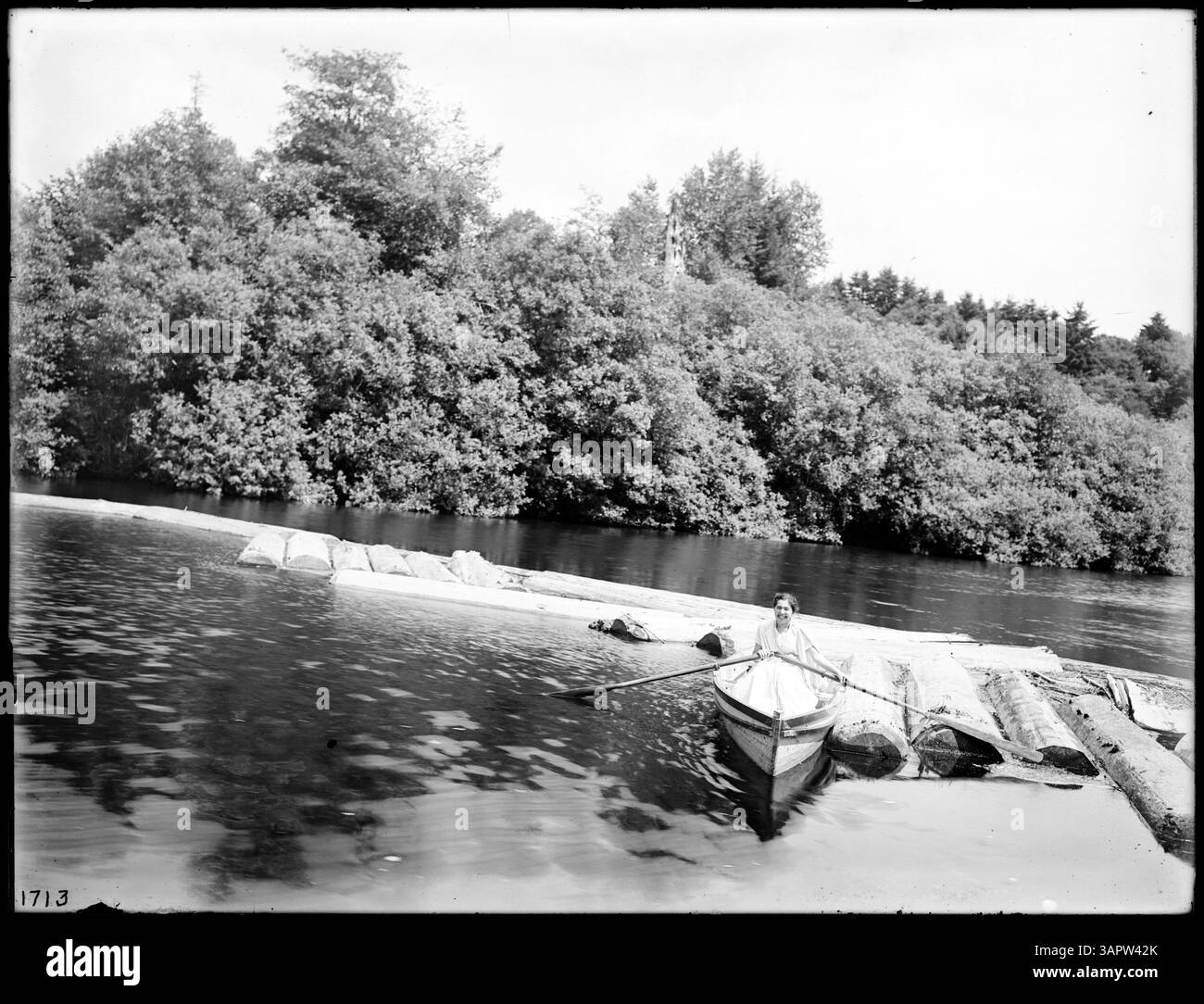 A woman is pictured in a rowboat, surrounded by a log boom, on the ...