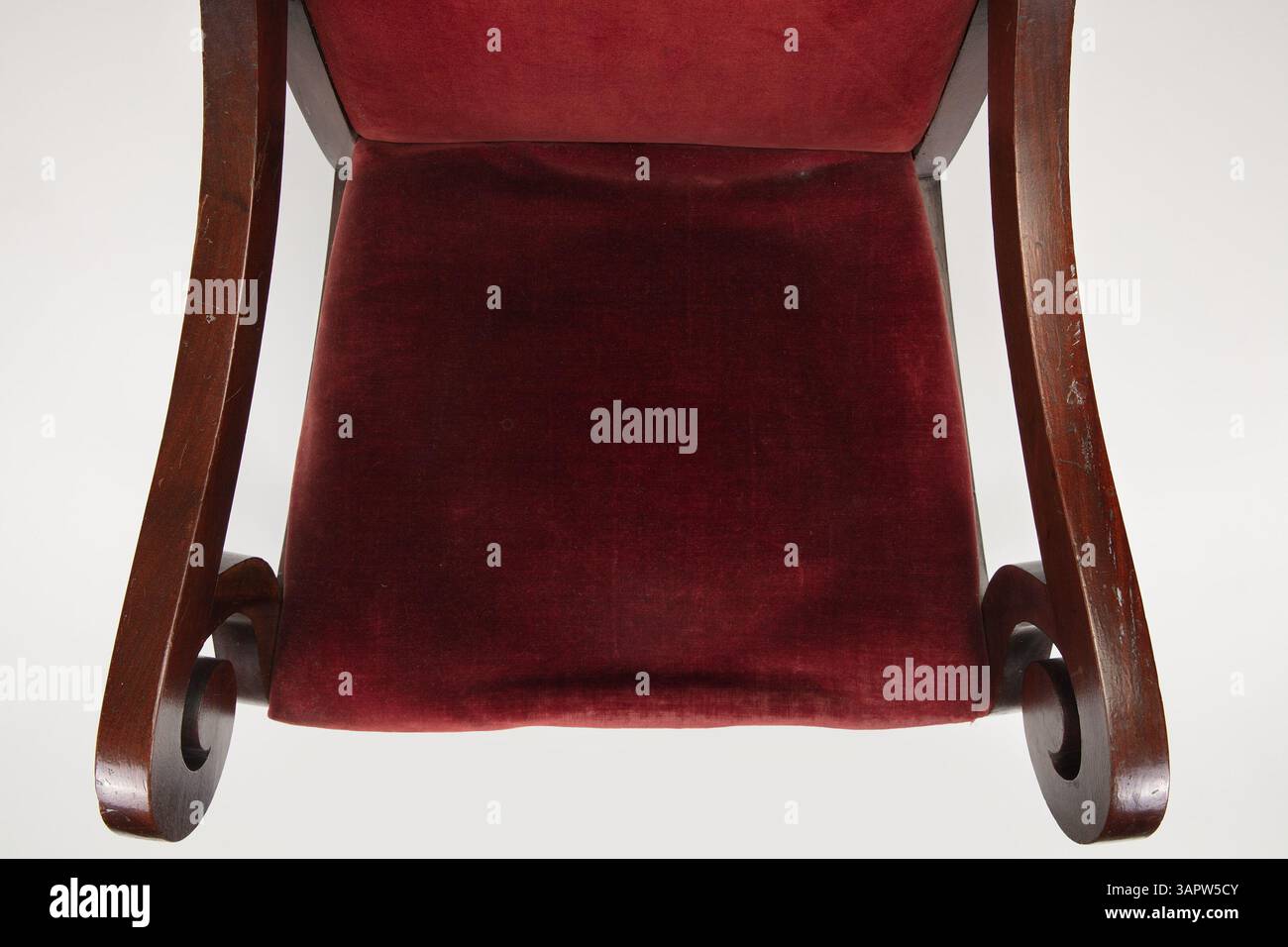 A high-backed priest's chair featuring a red velvet upholstered seat ...