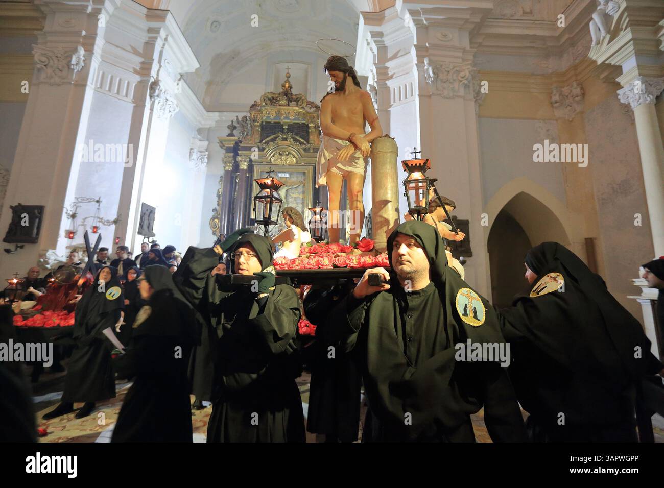 Black-clad and hooded faithful take part in the procession on Friday of ...