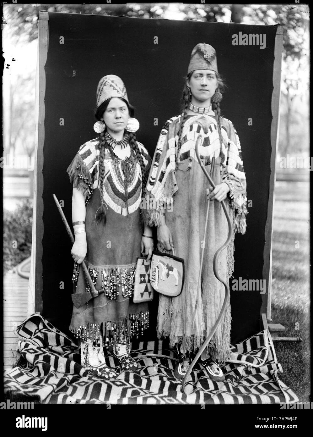 The photograph depicts two tribal women posed in traditional regalia ...