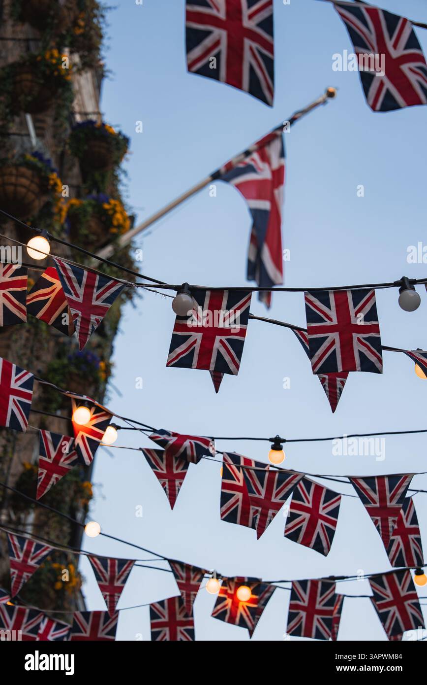Union Jack Flags and String Lights with Building and Flowers in London ...