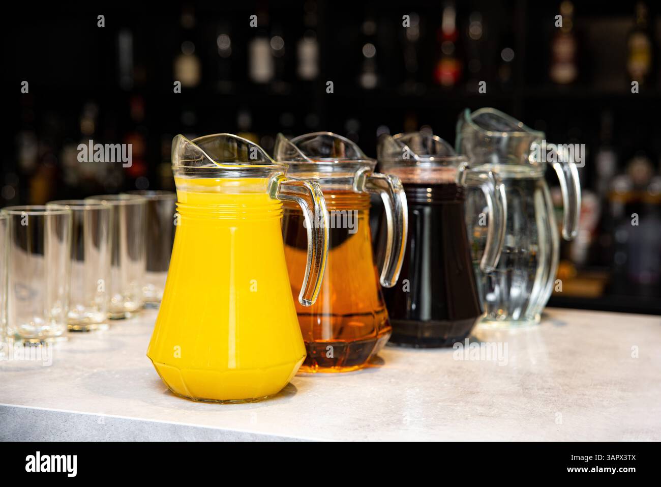 Four glass pitchers filled with different drinks - orange juice, iced ...