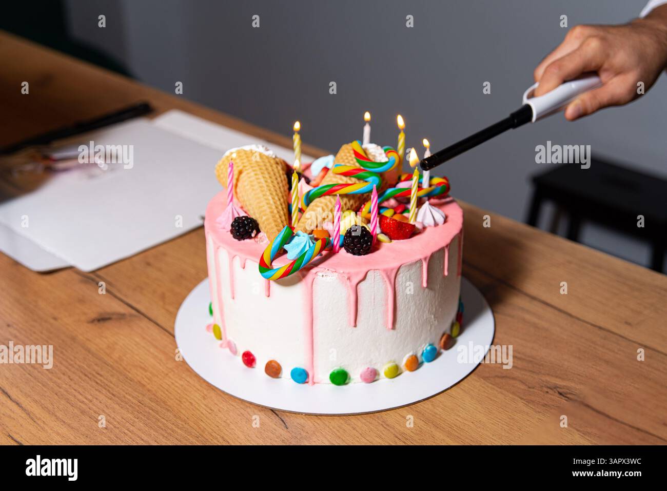 Hand lighting candles on vibrant birthday cake decorated with candies ...