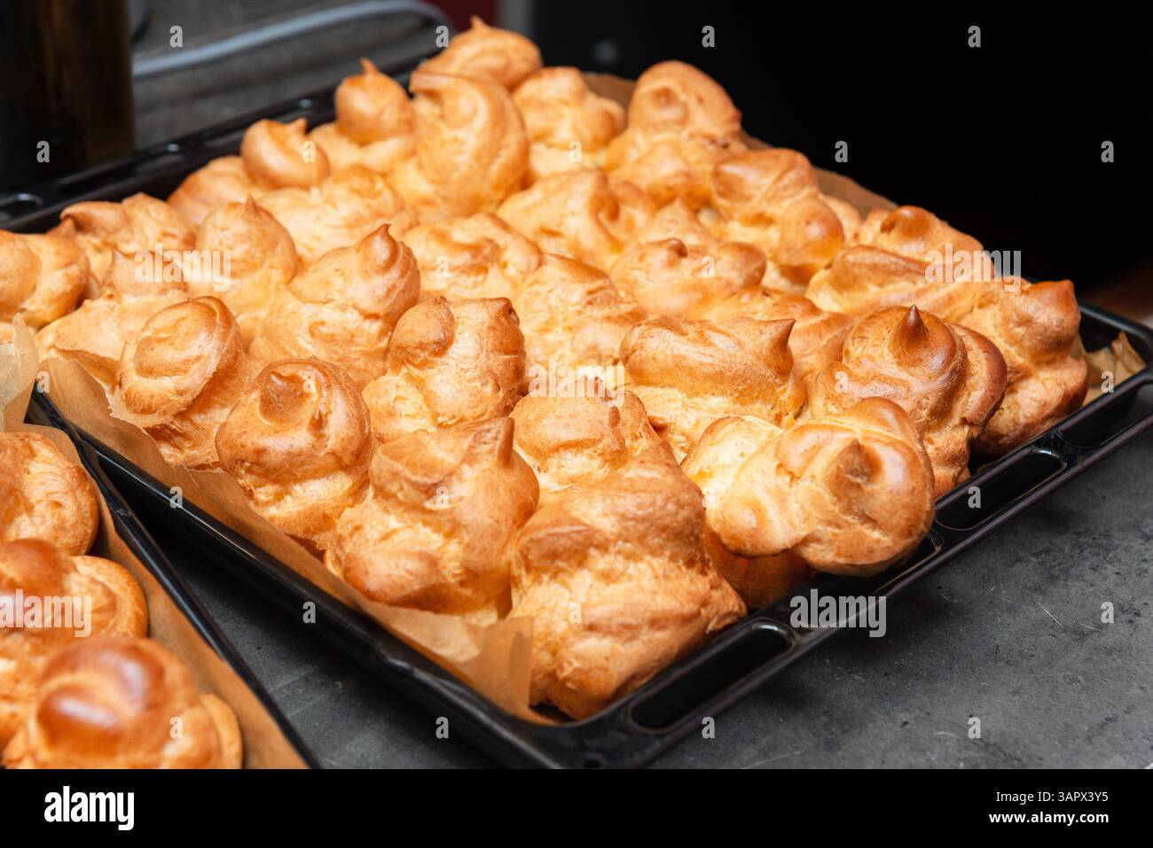 Freshly baked choux pastry puffs with a golden crust, cooling on a ...