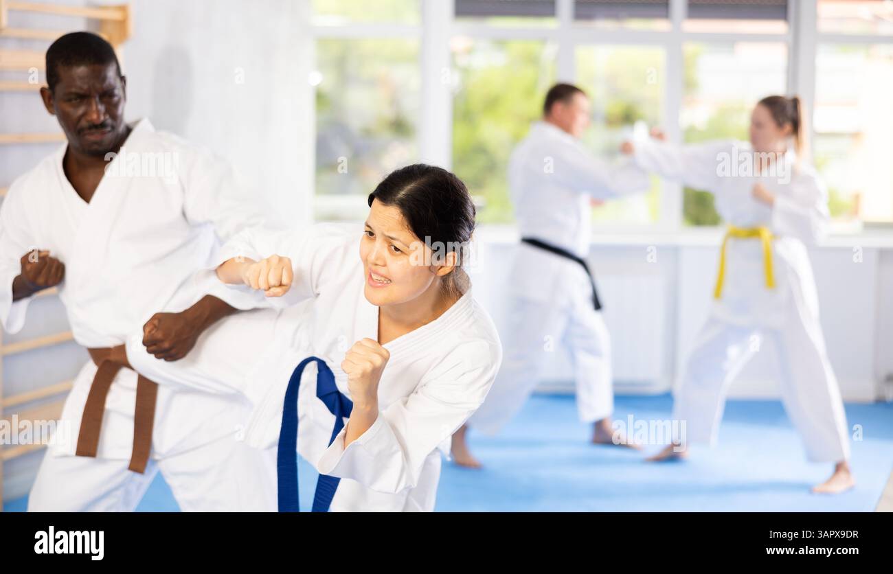 Middle-aged woman attendee of karate classes fighting with her opponent ...