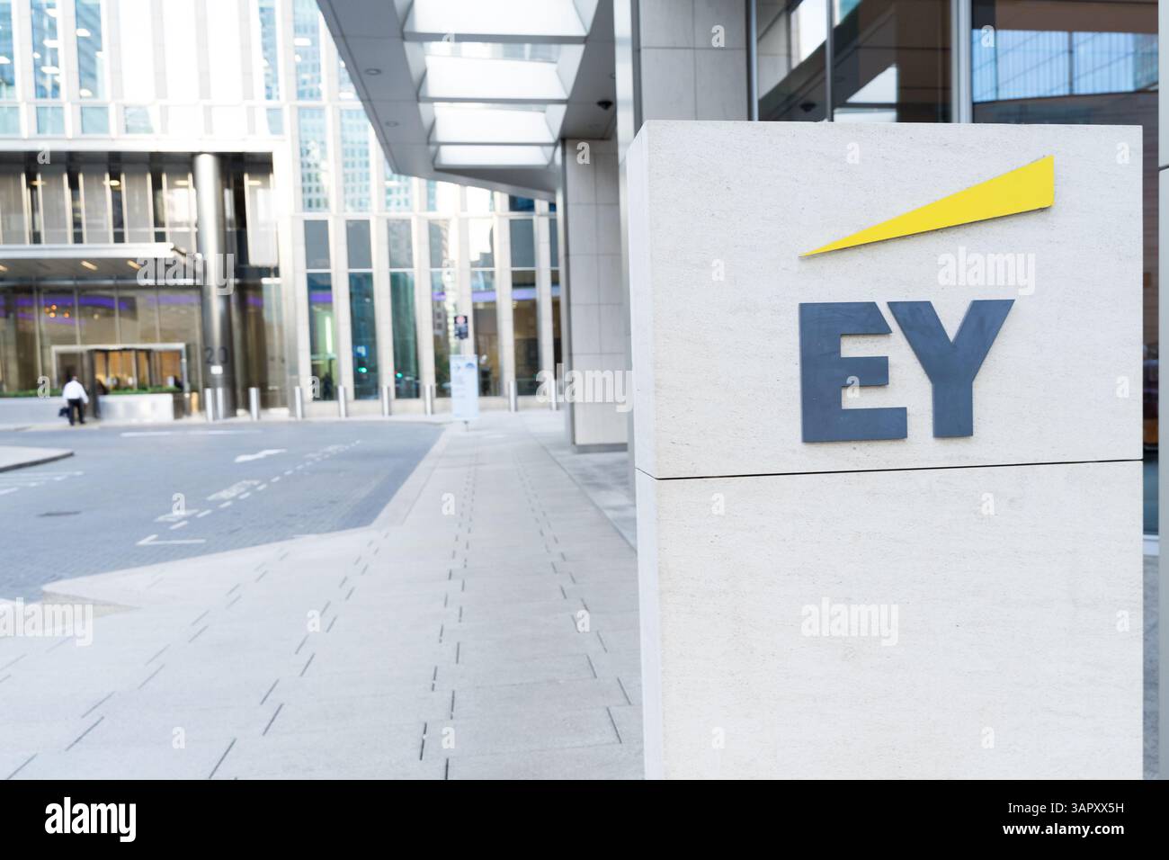 Logo EY branding name in yellow and black engraved on wall at entrance ...