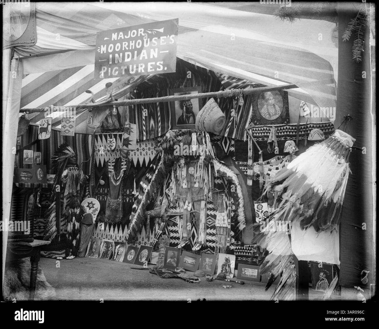 This photograph shows a wood-framed structure covered with striped tent ...