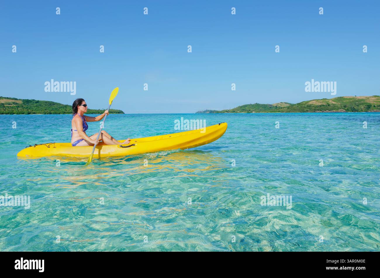 Woman sea kayaking in Fiji islands turquoise water, Waya island, Yasawa ...