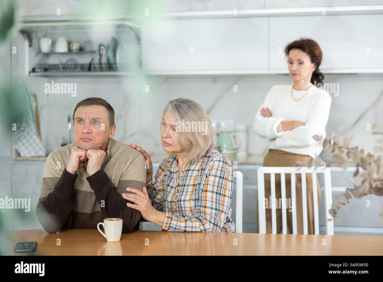 Family members quarreling in the kitchen and old woman trying to calm ...