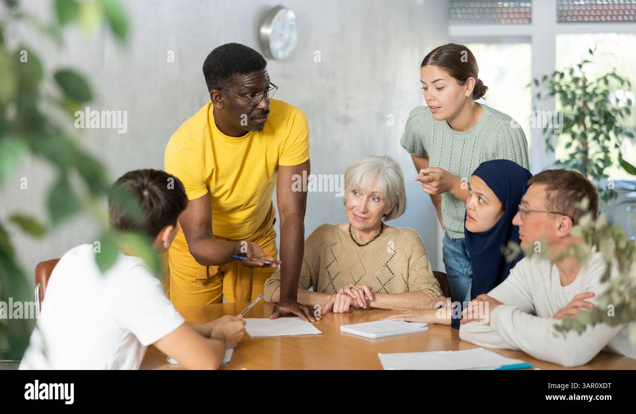 African American tutor conducting lesson for group of adult people ...