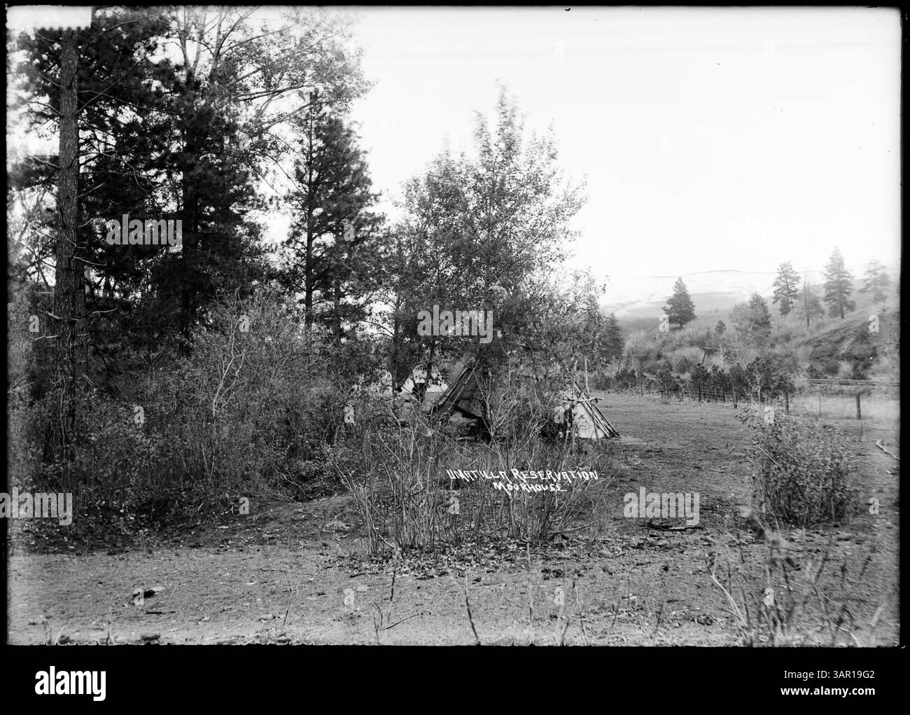 Two tipis are shown near trees and a barbed-wire fence, capturing ...
