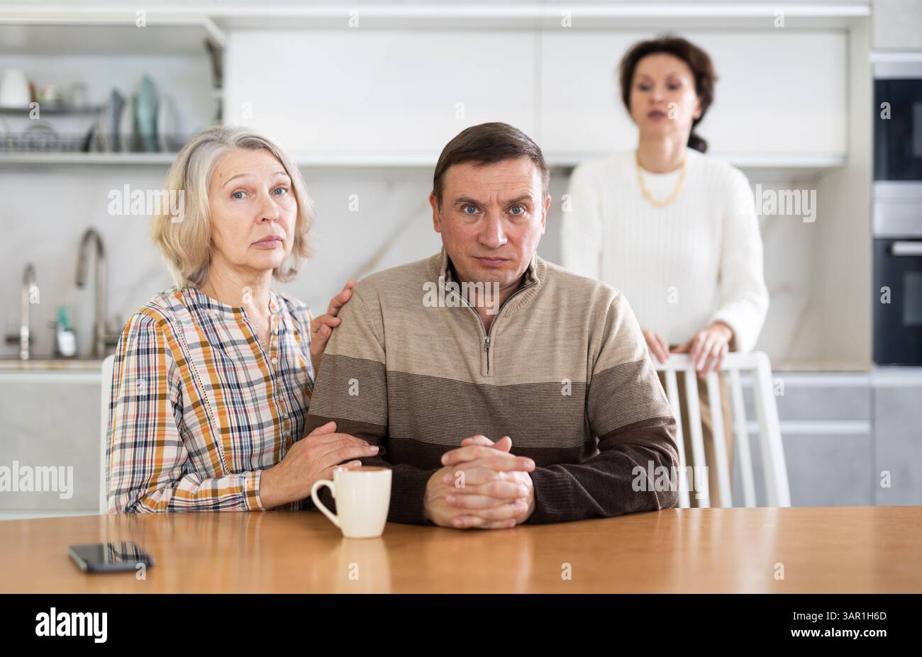 Family members quarreling in the kitchen and old woman trying to calm ...