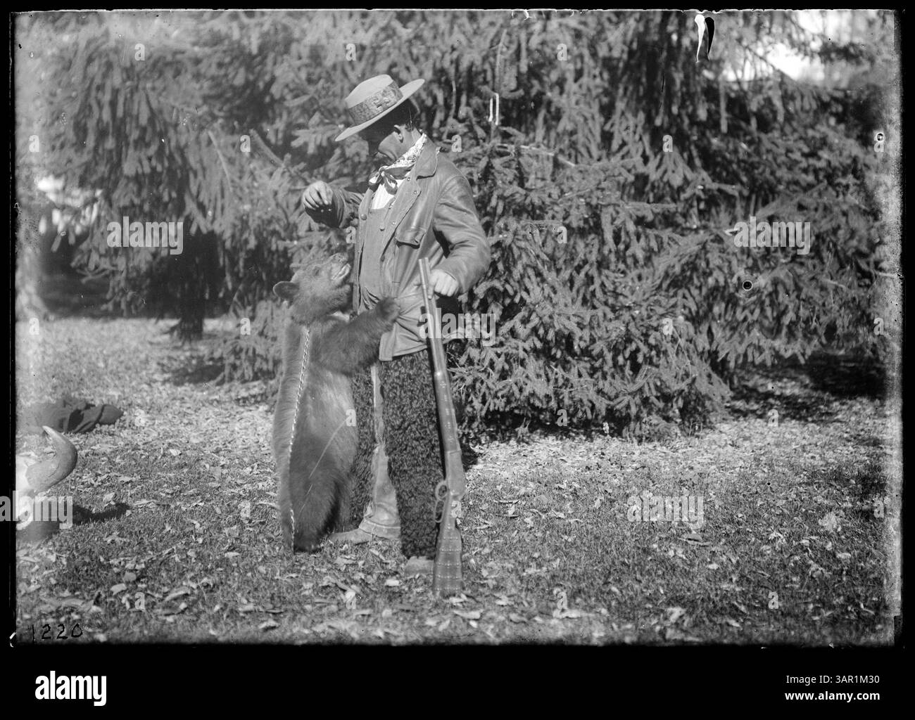 This photograph shows a man with a tame, chained bear, highlighting the ...