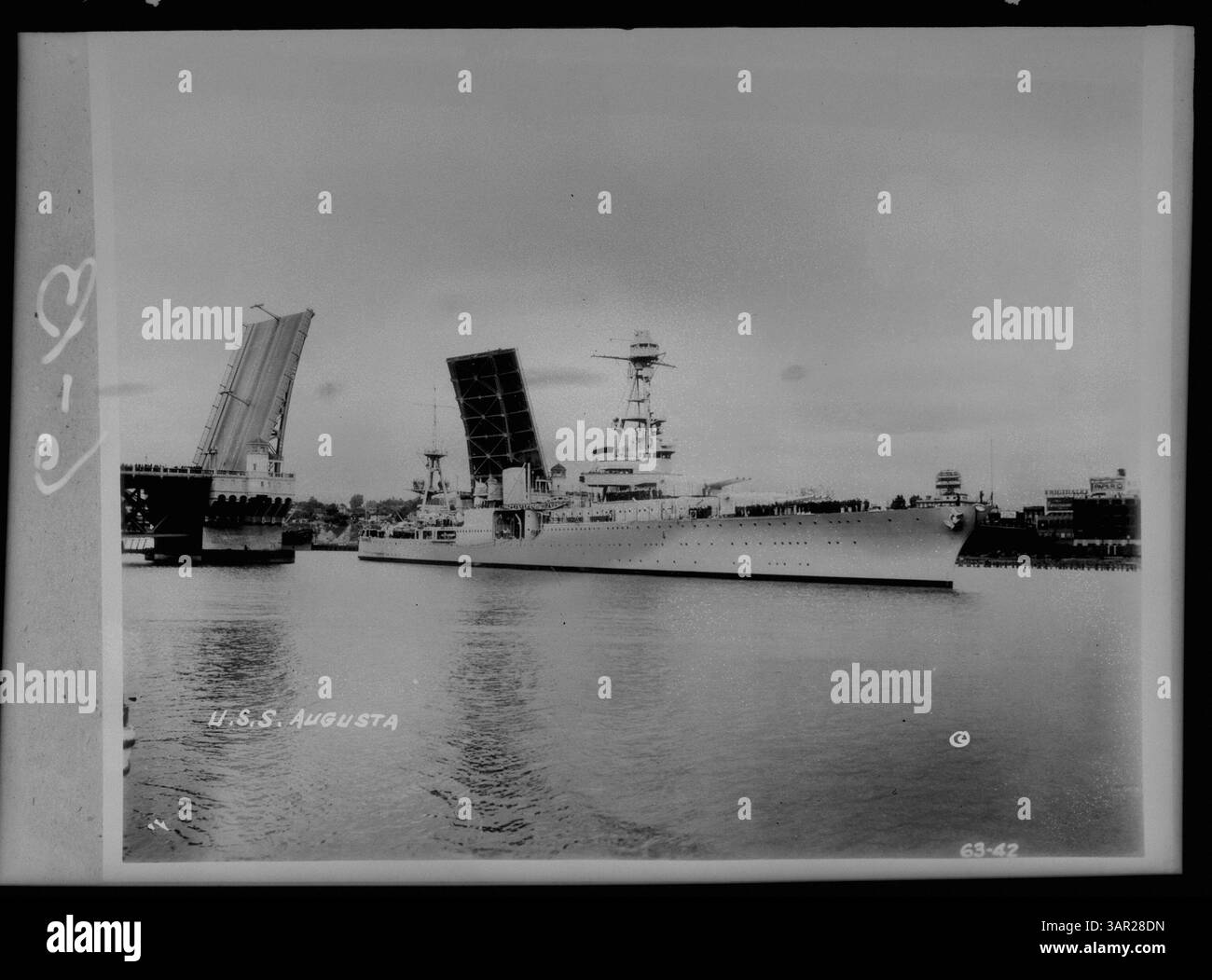 This photograph depicts the USS Augusta passing under a drawbridge. It ...