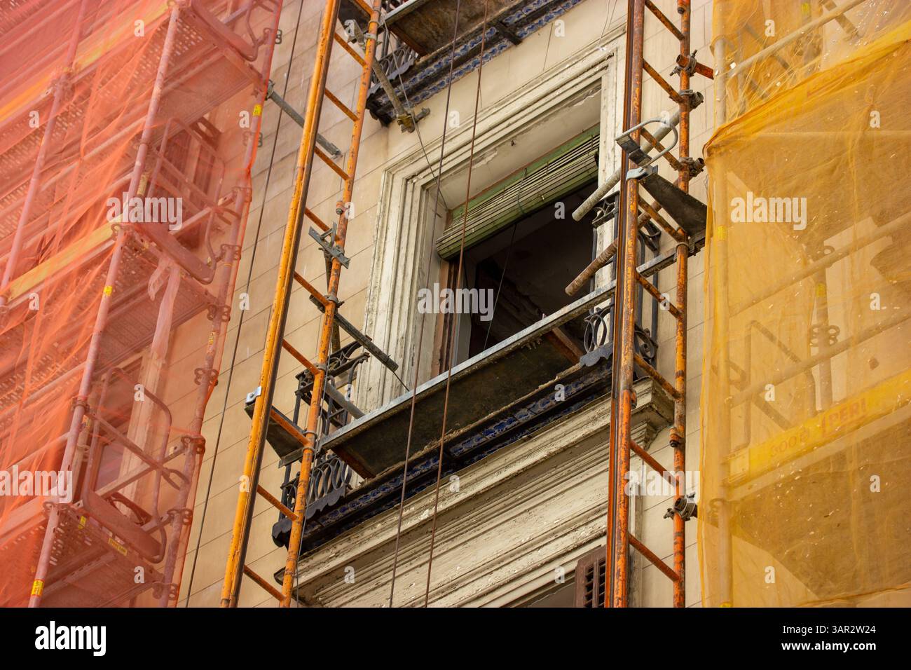 An urban facade displays construction scaffolding wrapped in safety ...