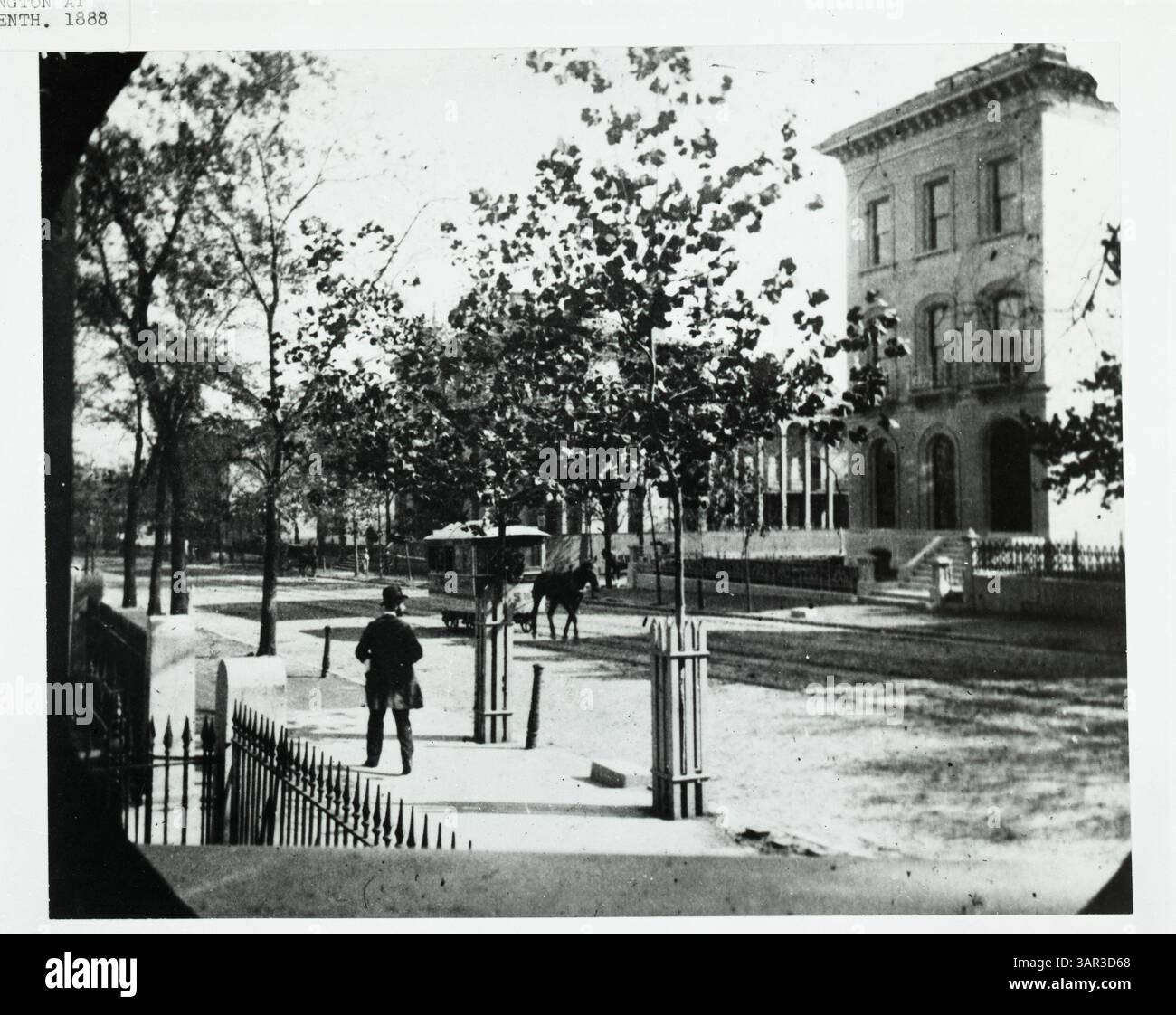This black and white photograph captures a man walking along the ...