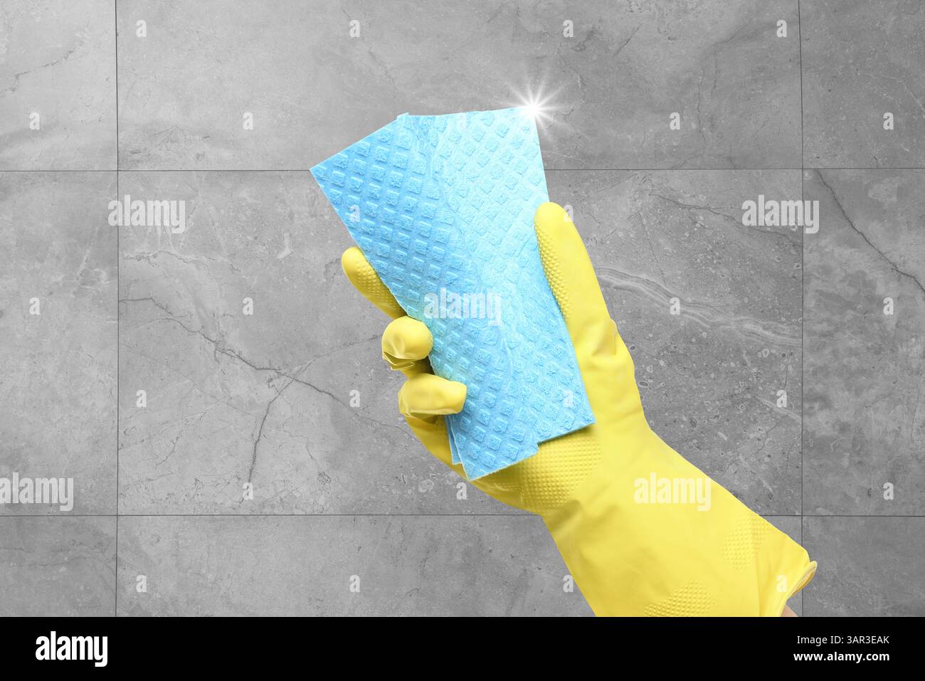 Cleaning service worker in rubber glove holding rag near grey tiled ...