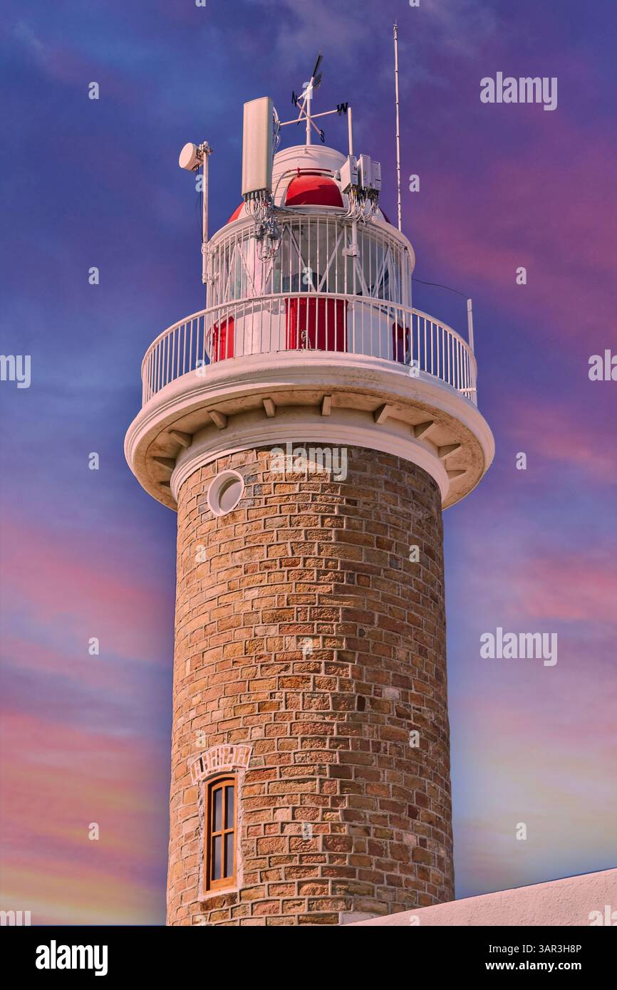 Old brick lighthouse with a white and red top, surrounded by a railing ...