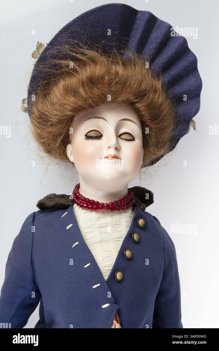 A bisque doll dressed in a blue skirt and jacket with a matching hat ...