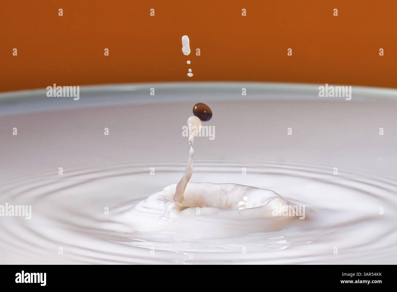 A drop with a splash in an orange environment creates dynamic fluid ...