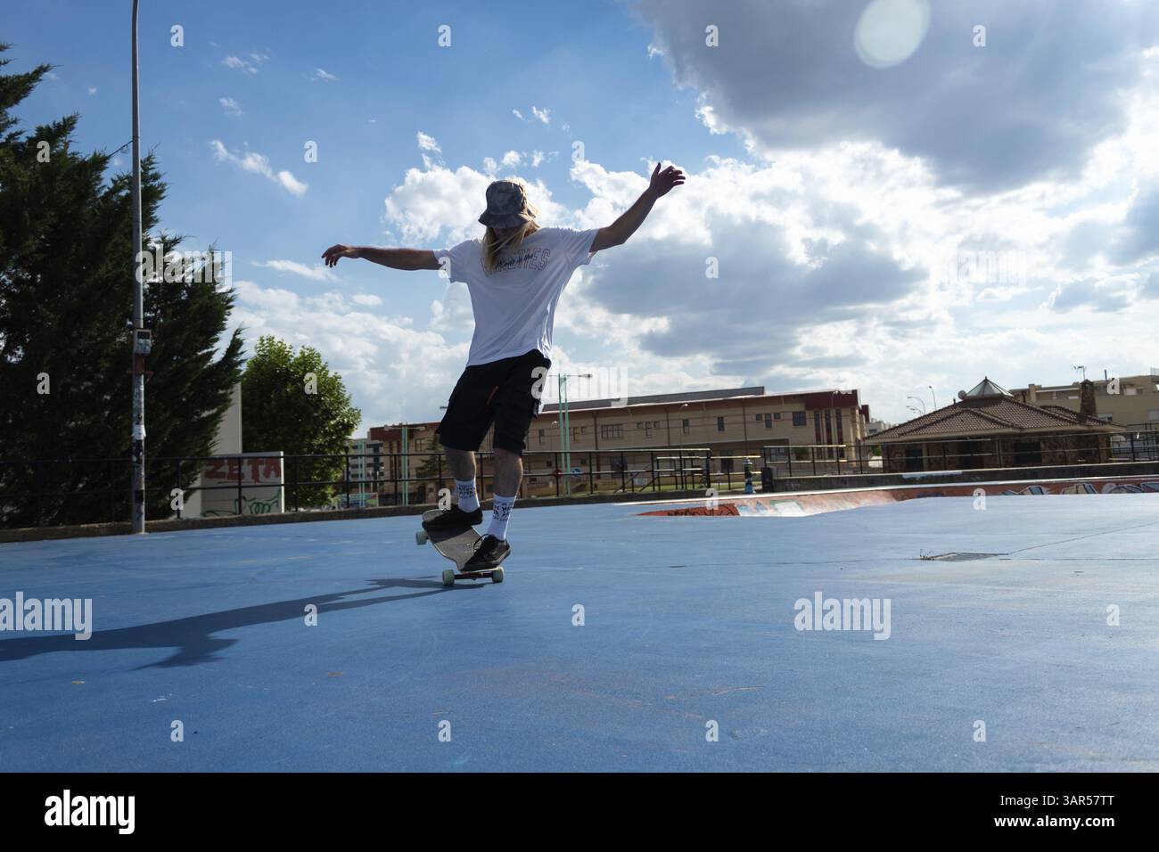 Young blond professional skateboarder with hat performing skate in ...