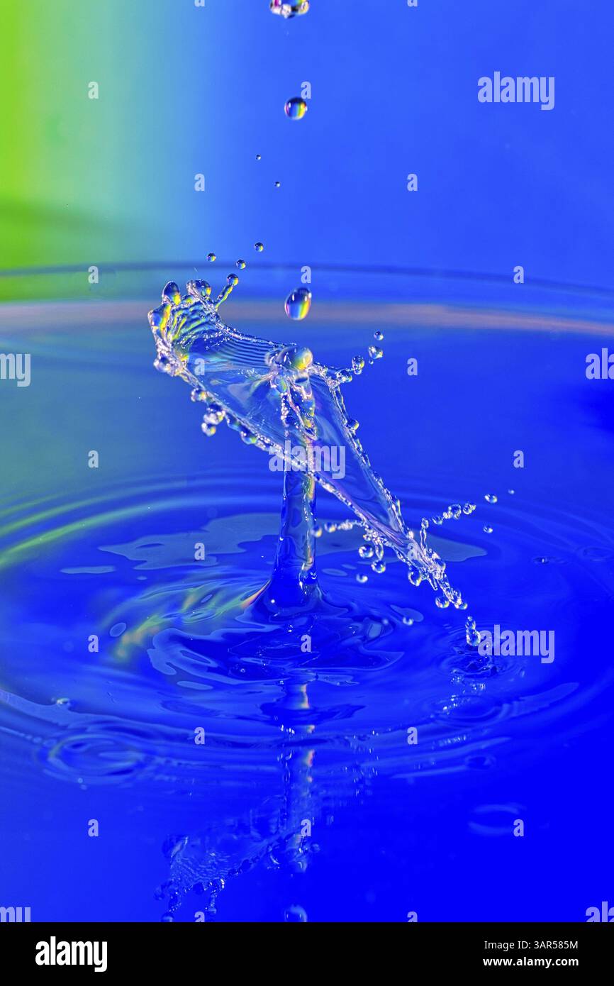 A blue drop meets liquid with vivid splash patterns, water droplets ...