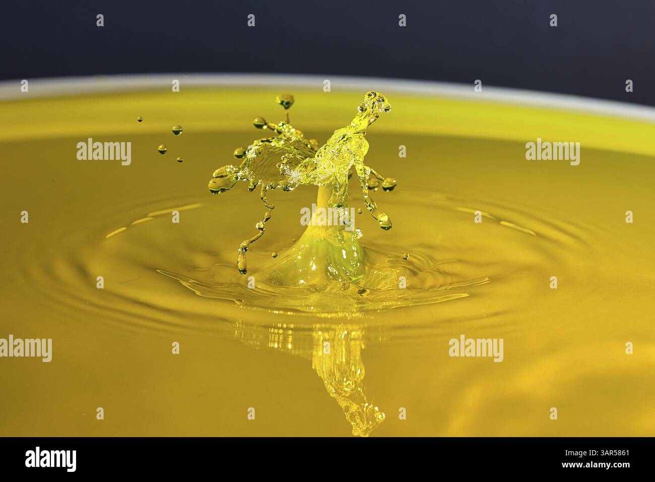 Water droplet creates pattern of yellow water on yellow surface, water ...