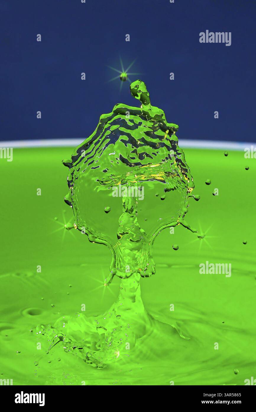 Green water drop forming a complex shape and glittering reflections in ...