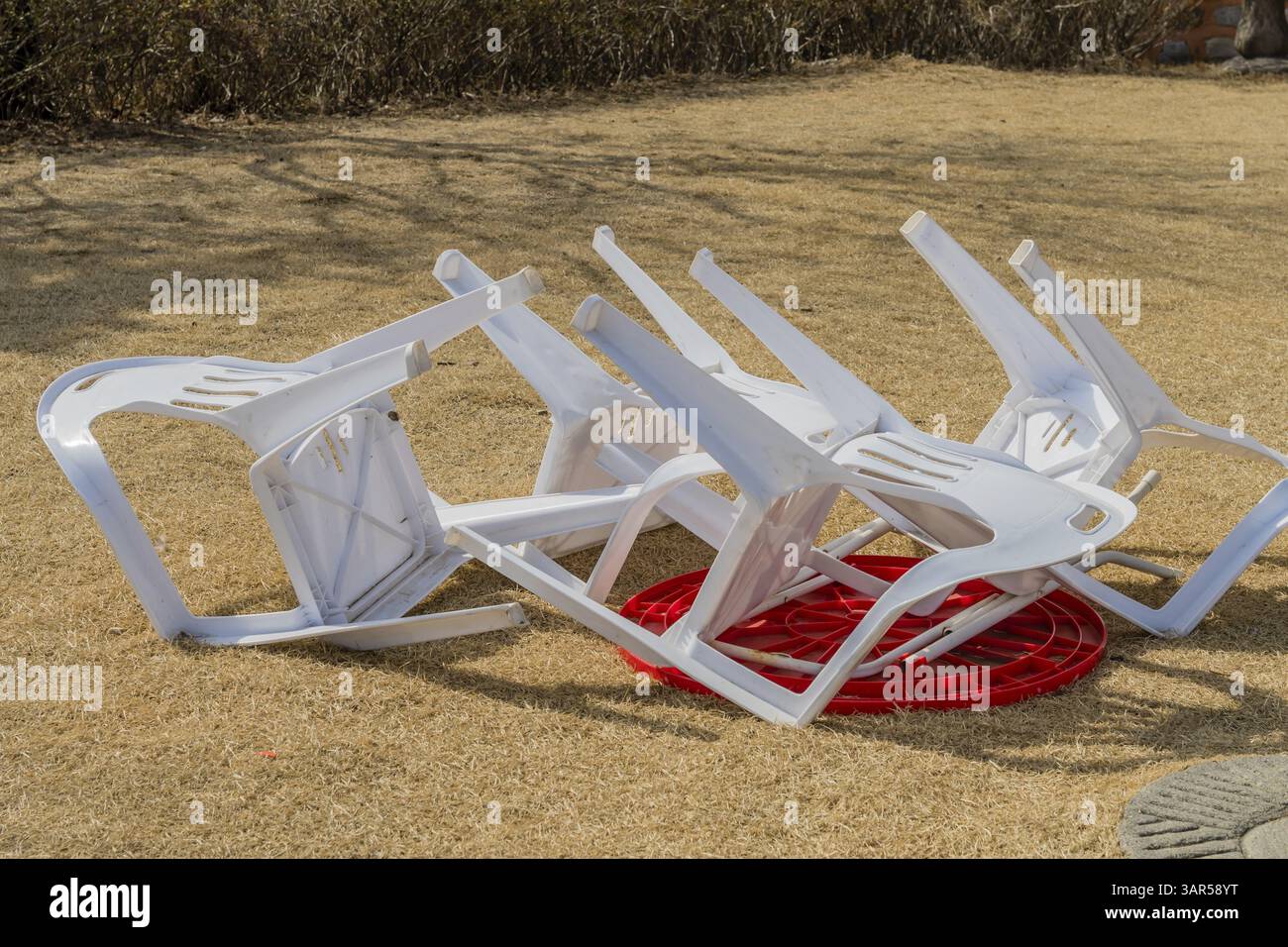 White plastic chairs turned over on top of red plastic table. Chungju ...