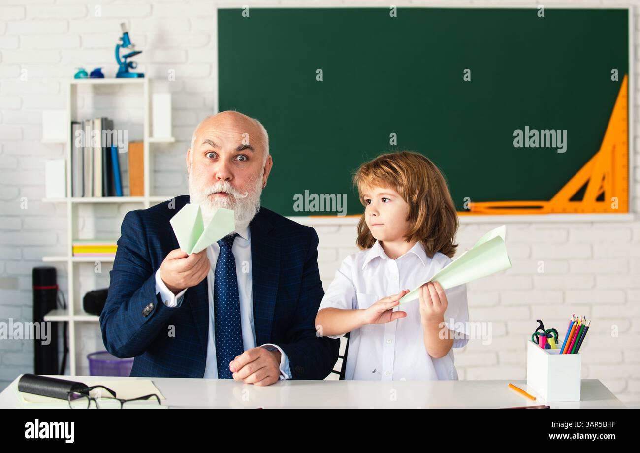Happy kid in school break. Senior teacher with pupil with paper plane ...