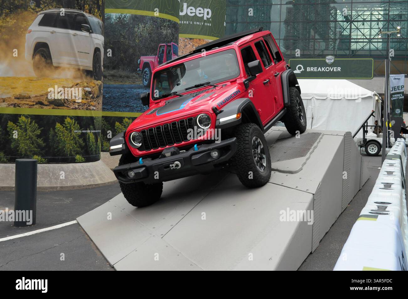 A person drives a Jeep Wrangler Rubicon down a ramp at an exhibition on ...