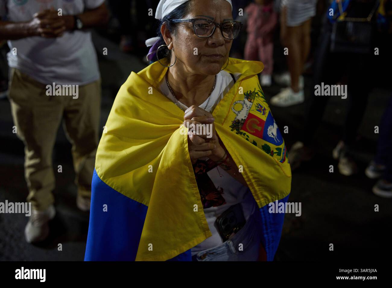 A devotee wrapped with a Venezuelan flag prays during the Nazarene of ...